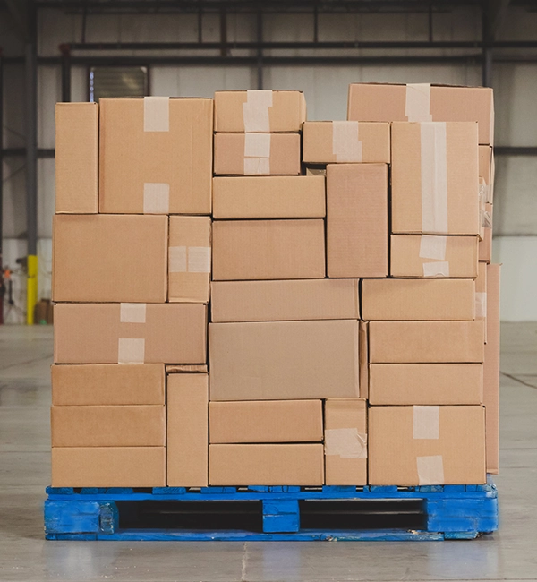 Many boxes stacked together on a pallet in a warehouse.